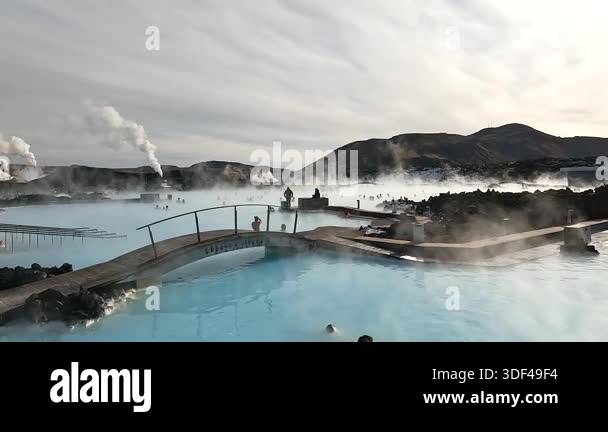 People enjoy soaking in warm, mineral-rich waters at a geothermal spa in Iceland. The sun sets ...