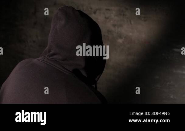 Anonymous hooded hacker with back to camera during police interrogation ...