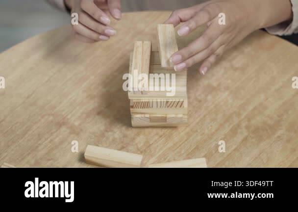Hands arranging wooden blocks to rebuild a tower after a collapse ...