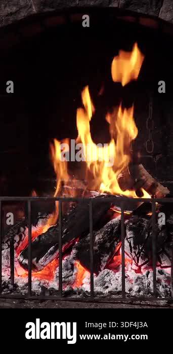 Vertical stone fireplace with a burning fire, close-up of a rustic ...