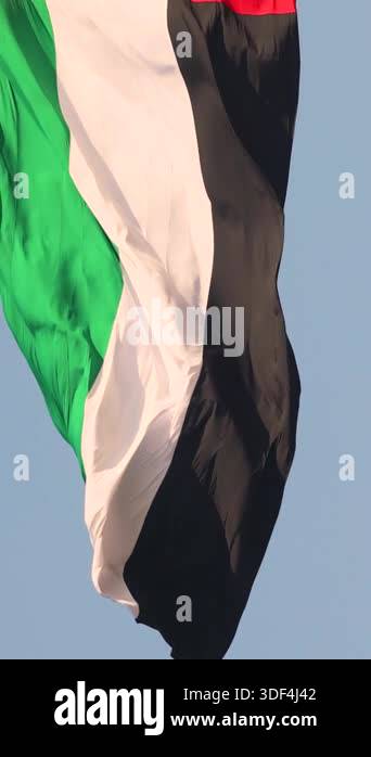 UAE flag waving in the wind against a bright blue sky with a white ...