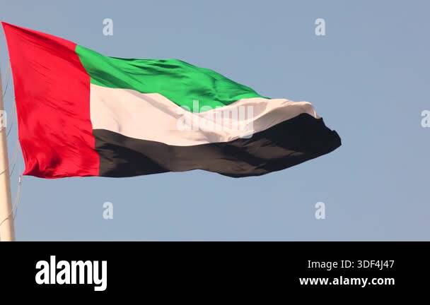 UAE flag waving in the wind against a bright blue sky with a white ...