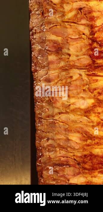 Close-up of rotating spit with meat sizzling on fire in open kitchen of ...