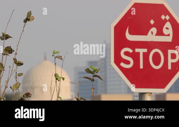 Red stop sign with Arabic explanation against UAE city skyline with ...