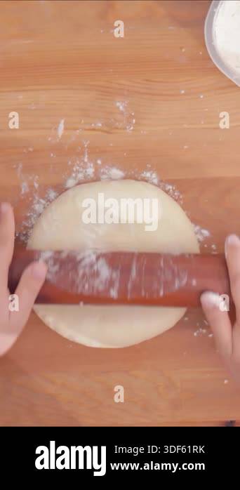 Woman baker is rolling out dough using wooden rolling pin on cozy ...