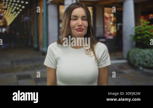 Young hispanic woman covering mouth with hand on busy city street ...