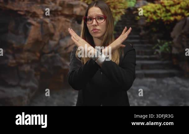 Woman wearing red glasses and black blazer arms crossed x gesture on ...
