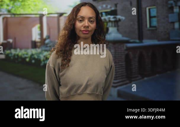 Woman face standing with eyes closed in front of brick building, casual ...