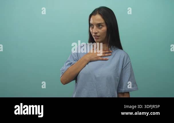 Woman touching her hand to chest, visible face and hand against a mint ...