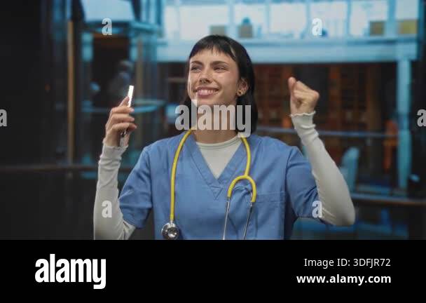 Woman wearing blue scrubs and stethoscope holding smartphone with ...