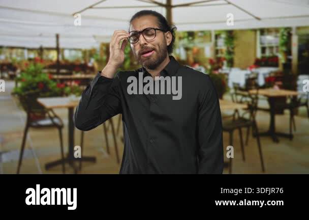 Man rubbing temple with hand at outdoor restaurant terrace, eyes closed ...