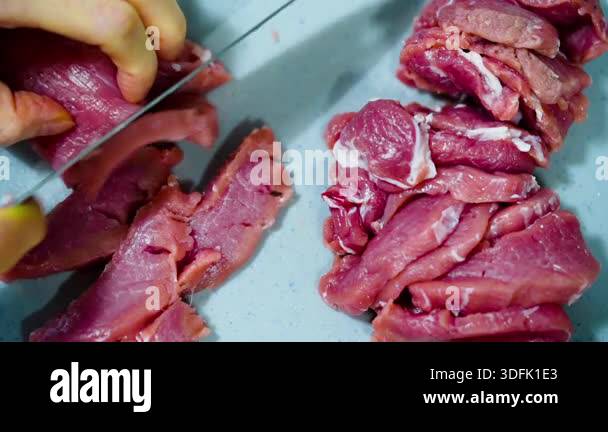 A female cuts a carcass of red meat. Cuts meat into slices. High ...