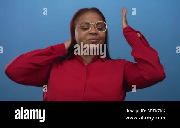 Woman wearing red blouse adjusts her hair and straightens eyeglasses in ...