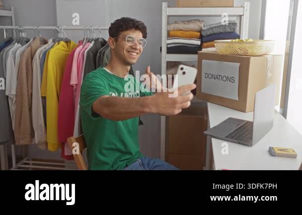 Young man wearing green volunteer shirt holding smartphone gestures ...