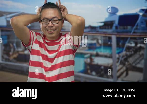 Man in red striped shirt and glasses makes bunny ears with fingers ...