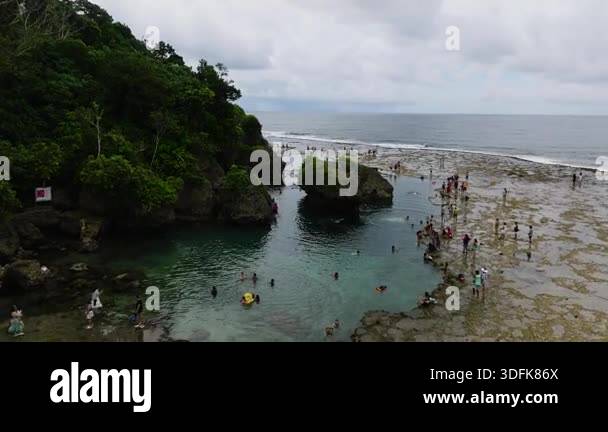 People swim and relax in lagoon formed by rocks along tropical ...