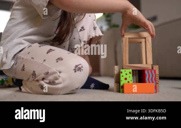 caucasian girl stacking wooden blocks on carpet, pajama outfit and cozy ...