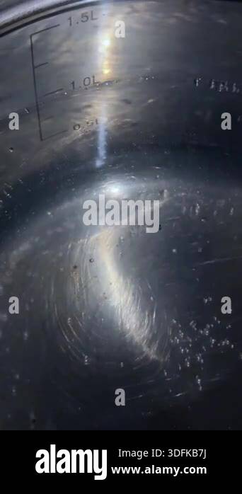 Water boiling in a metal measuring container marked 0.5L and 1.0L close ...