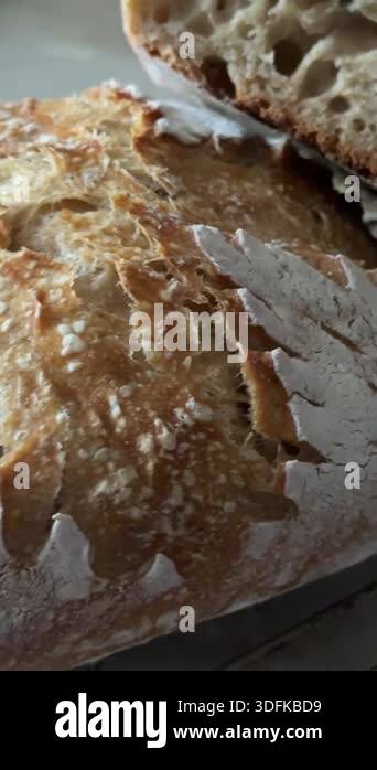 A whole and sliced loaf of artisan bread with a porous crumb and crispy ...