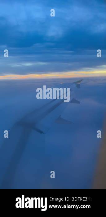 4K. A passenger plane flies through the clouds at sunset, view from the ...