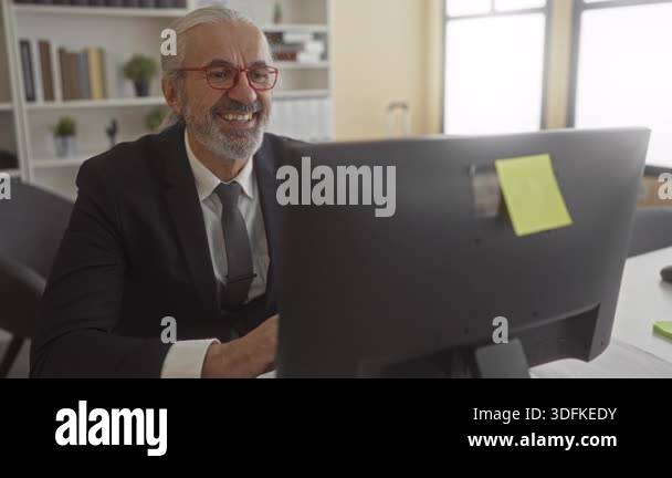 Man smiling and raising fists at computer monitor while seated at desk ...