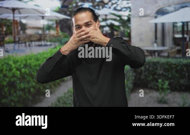 Young arab hispanic man covers mouth with both hands on a restaurant ...