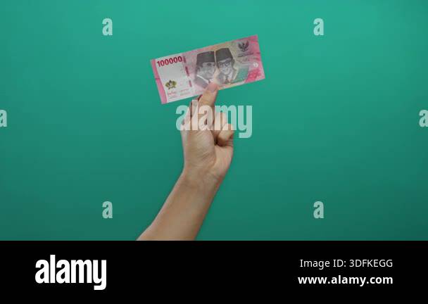 Hand holding indonesian rupiah against green wall conveys financial ...