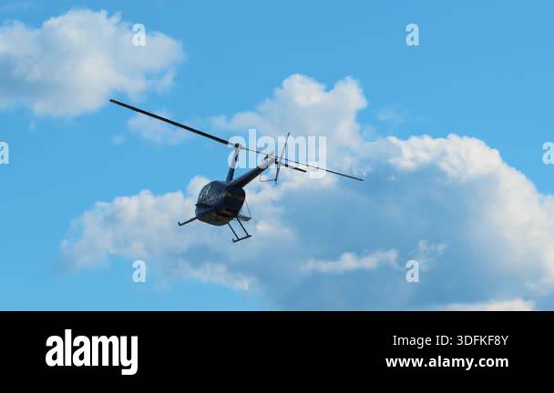 Helicopter flies across the sky, banking slightly as it passes through ...