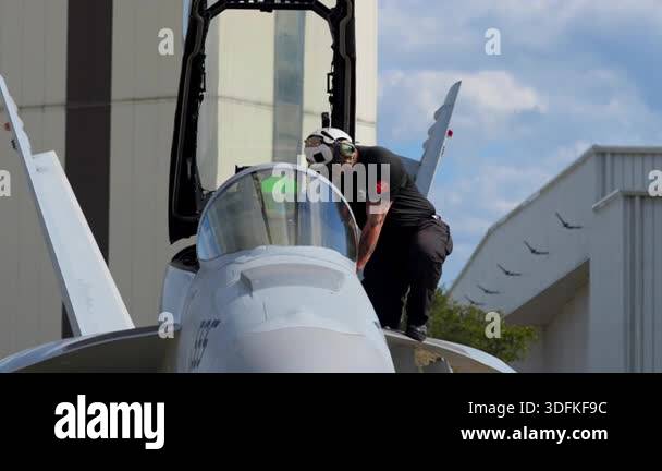 Military pilot climbs into a fighter jet cockpit during ground ...