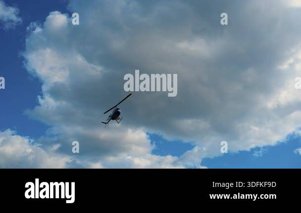 Helicopter flies across the sky, banking slightly as it passes through ...