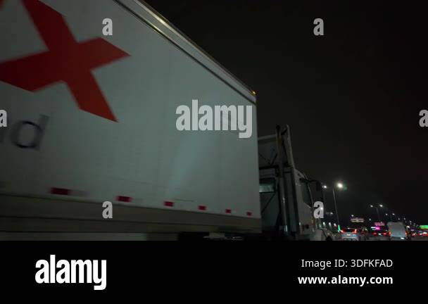 Night highway drive beside a FedEx Ground semi-truck. Night roadway ...