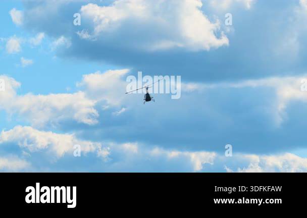 Helicopter flies across sky, banking slightly as it passes through ...