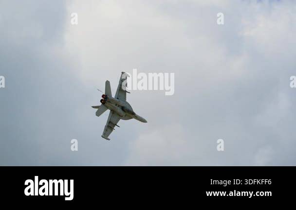 Military fighter jet fly overhead against a blue sky with stormy clouds ...