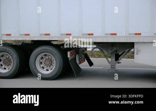 POV Close tracking shot of semi-truck trailer and rear wheels moving on ...