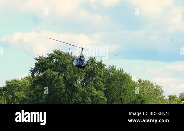 Helicopter flies over the trees, banking slightly . Dramatic view of an ...