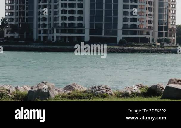 Small utility boat moving across a calm urban waterway with modern ...