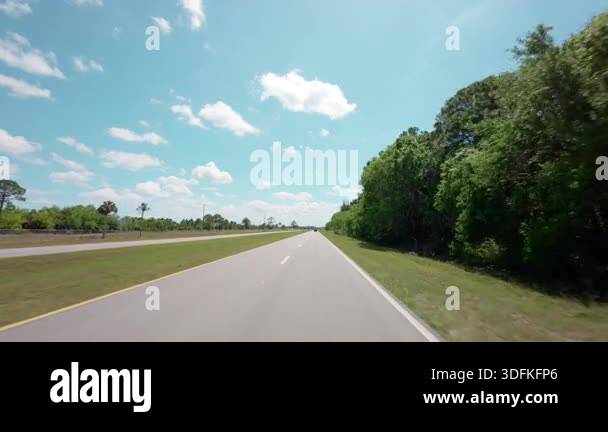 POV of driving footage on a spring highway under a clear blue sky ...