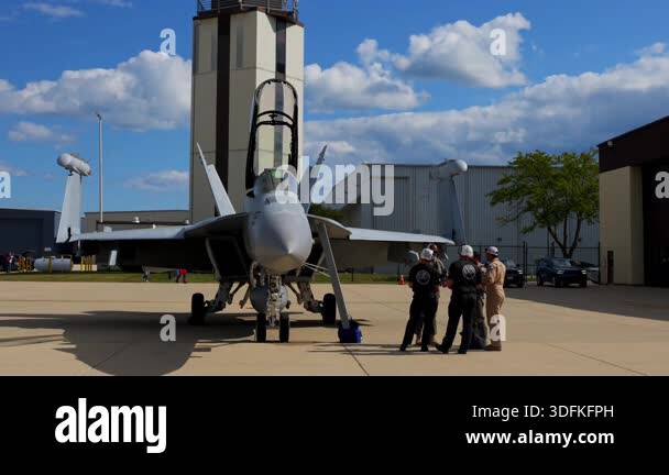 Military fighter jet parked on an airbase apron as ground crew members ...