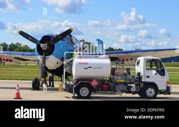 POV Ground crew refuels a vintage propeller aircraft on airport apron ...