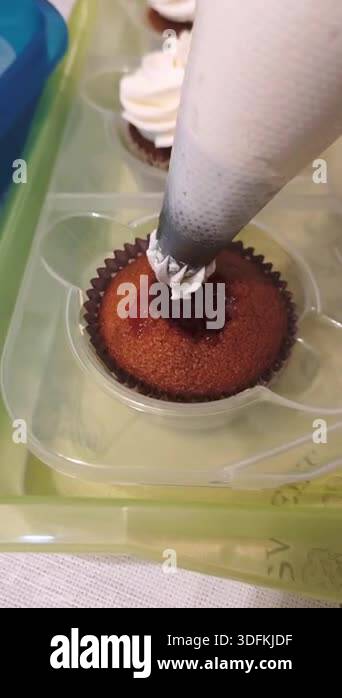 A pastry chef applies a fluffy cap of white buttercream to a chocolate ...