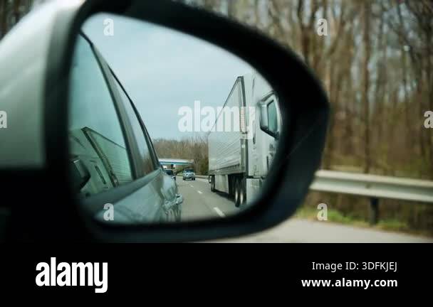 POV view. Reflection of white truck in the side mirror of driving car ...
