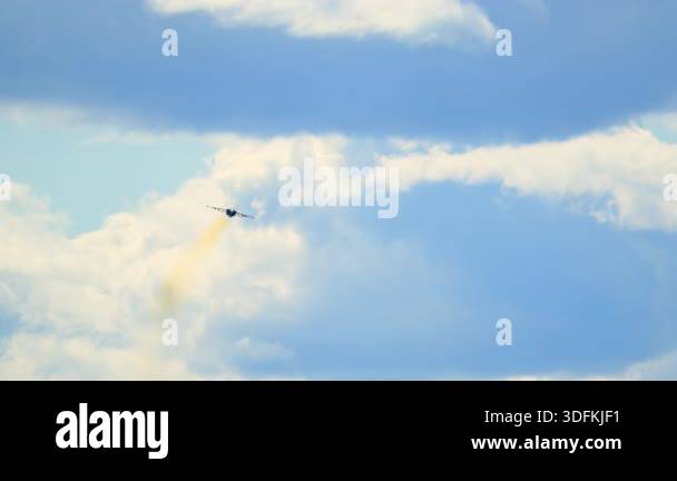 Military fighter jet flies through a cloudy blue sky, leaving a trail ...