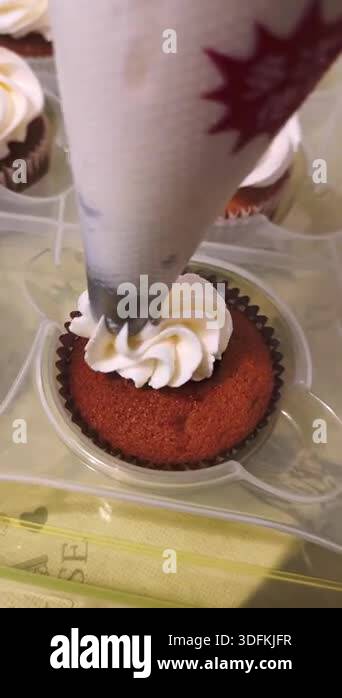 A pastry chef applies a fluffy cap of white buttercream to a chocolate ...