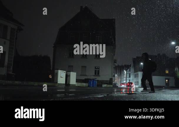 Individual Traversing Wet Road Midst Falling Snow, Figure Moves ...
