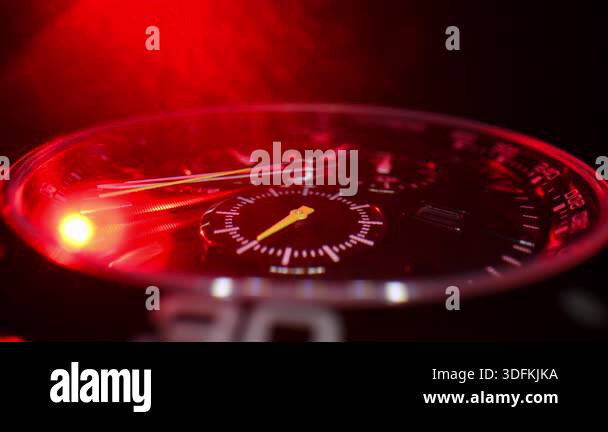 Macro close-up of a luxury chronograph watch illuminated by intense red ...