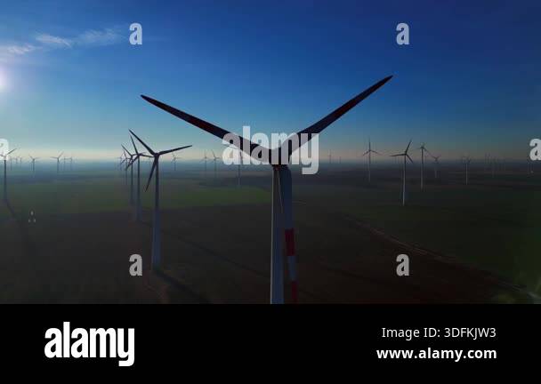 Wind turbine hub and blades closeup with array of turbines generating ...