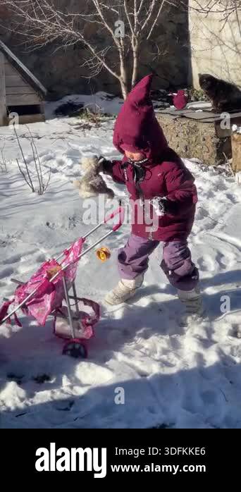 Child In Purple Snowsuit Pushing Pink Toy Stroller Through Sunny ...