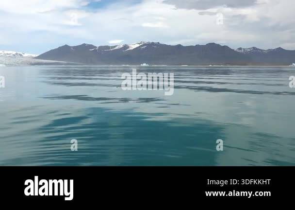 Point of view sailing across the calm water of a glacial lagoon with ...
