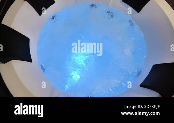 Jacuzzi. Blue bubbling water in a black and white round Jacuzzi bathtub ...