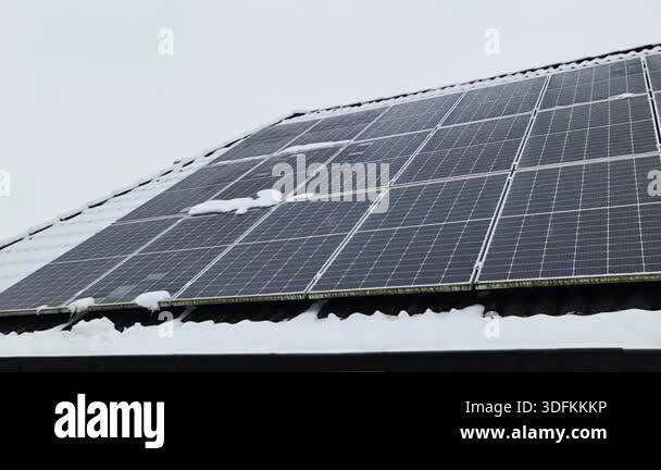 Solar panels on a house roof clearing themselves of snow during winter ...